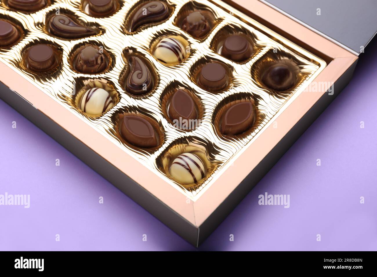 Box of delicious chocolate candies on violet background Stock Photo - Alamy