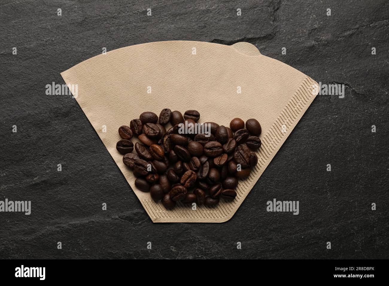 Paper coffee filter and beans on black table, top view Stock Photo - Alamy