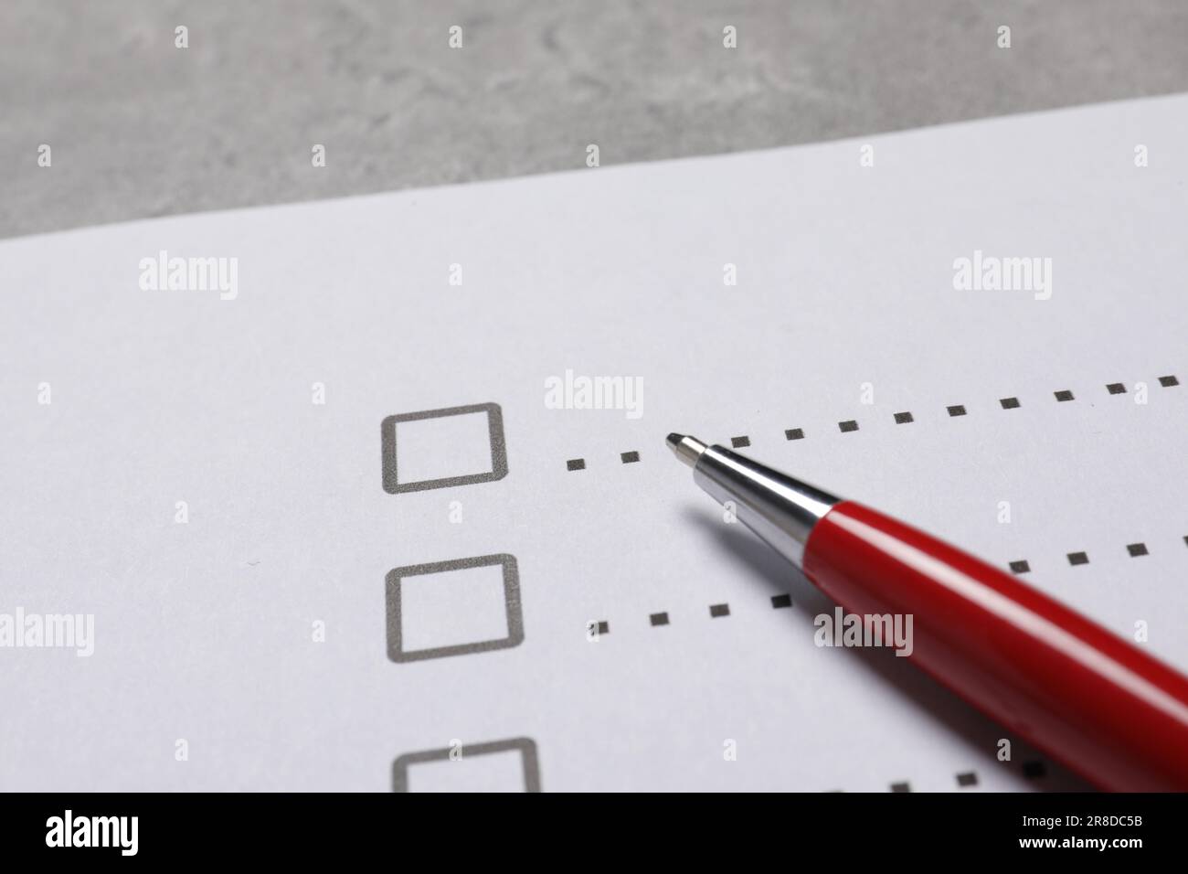 Paper sheet with checkboxes and pen on light grey table, closeup ...