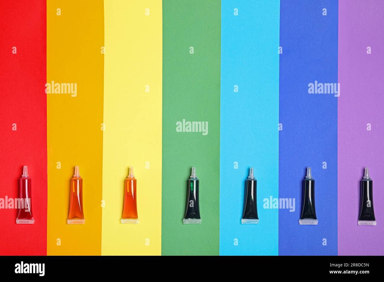 Tubes with different food coloring on rainbow background, flat lay ...