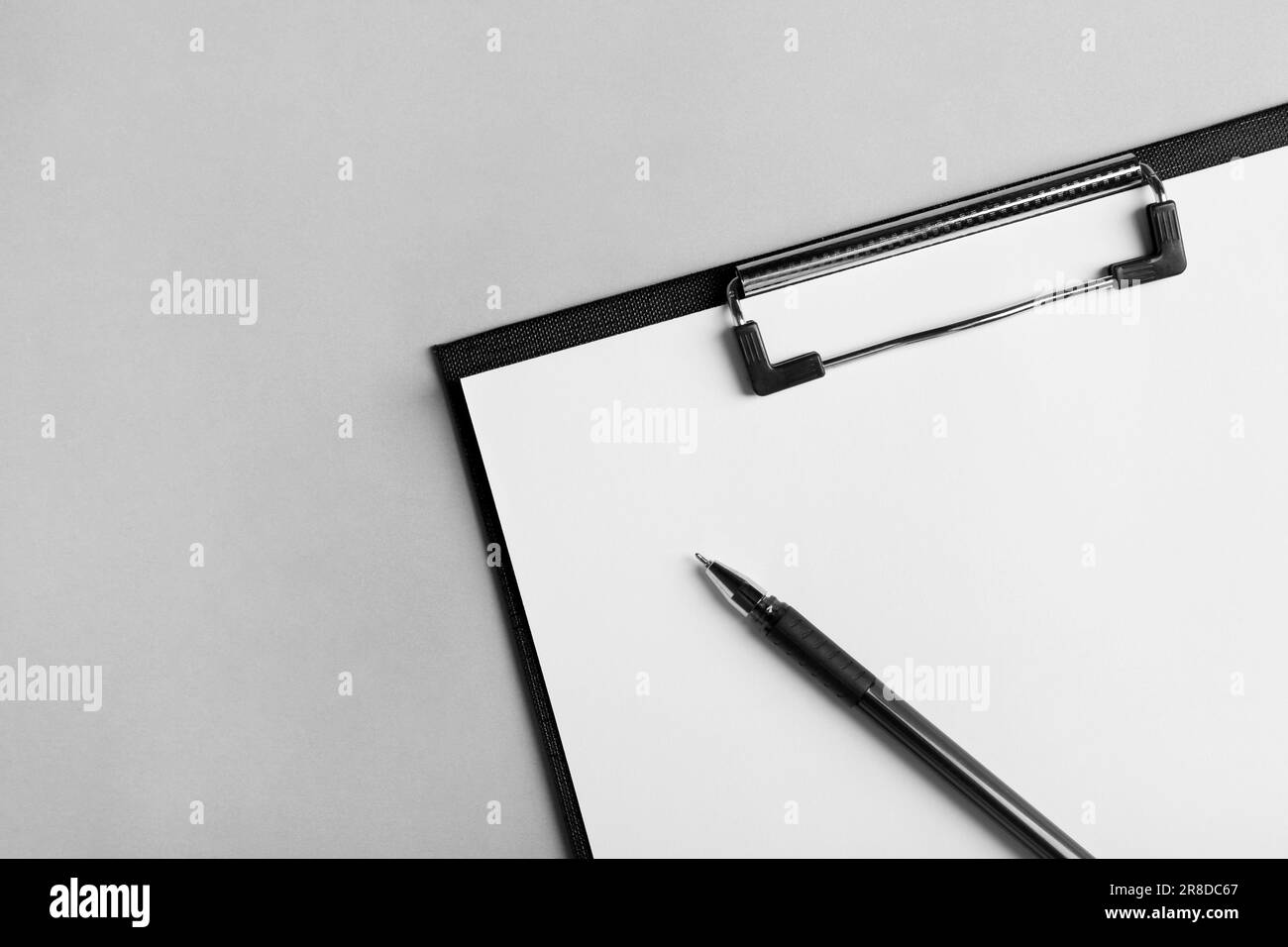 Black clipboard with sheet of blank paper and pen on light grey ...