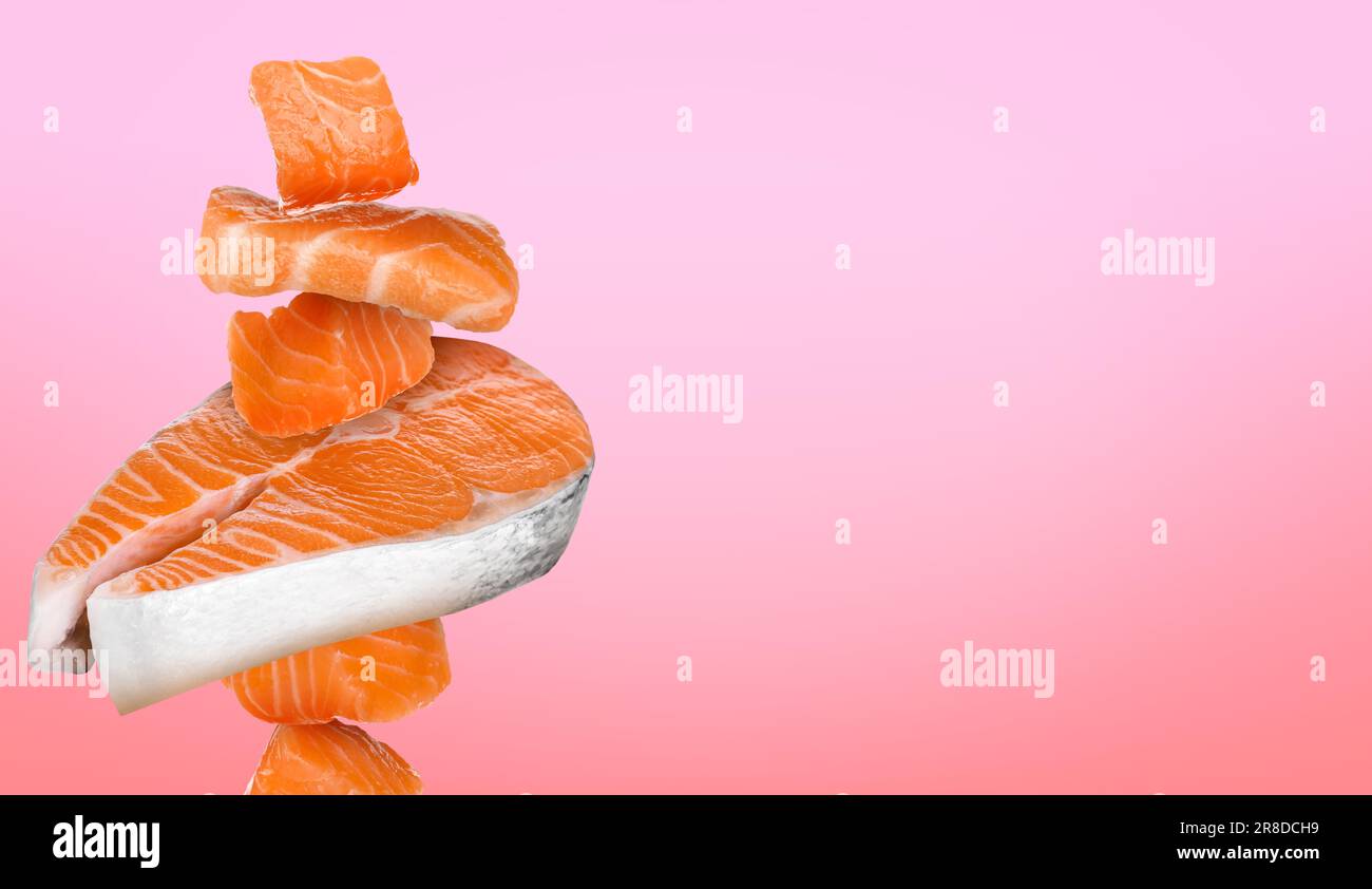 Cut fresh salmon falling on pink gradient background, space for text ...