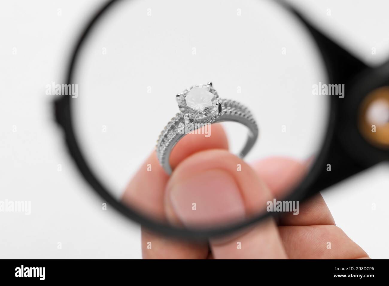 Jeweler examining diamond ring with magnifying glass on white ...