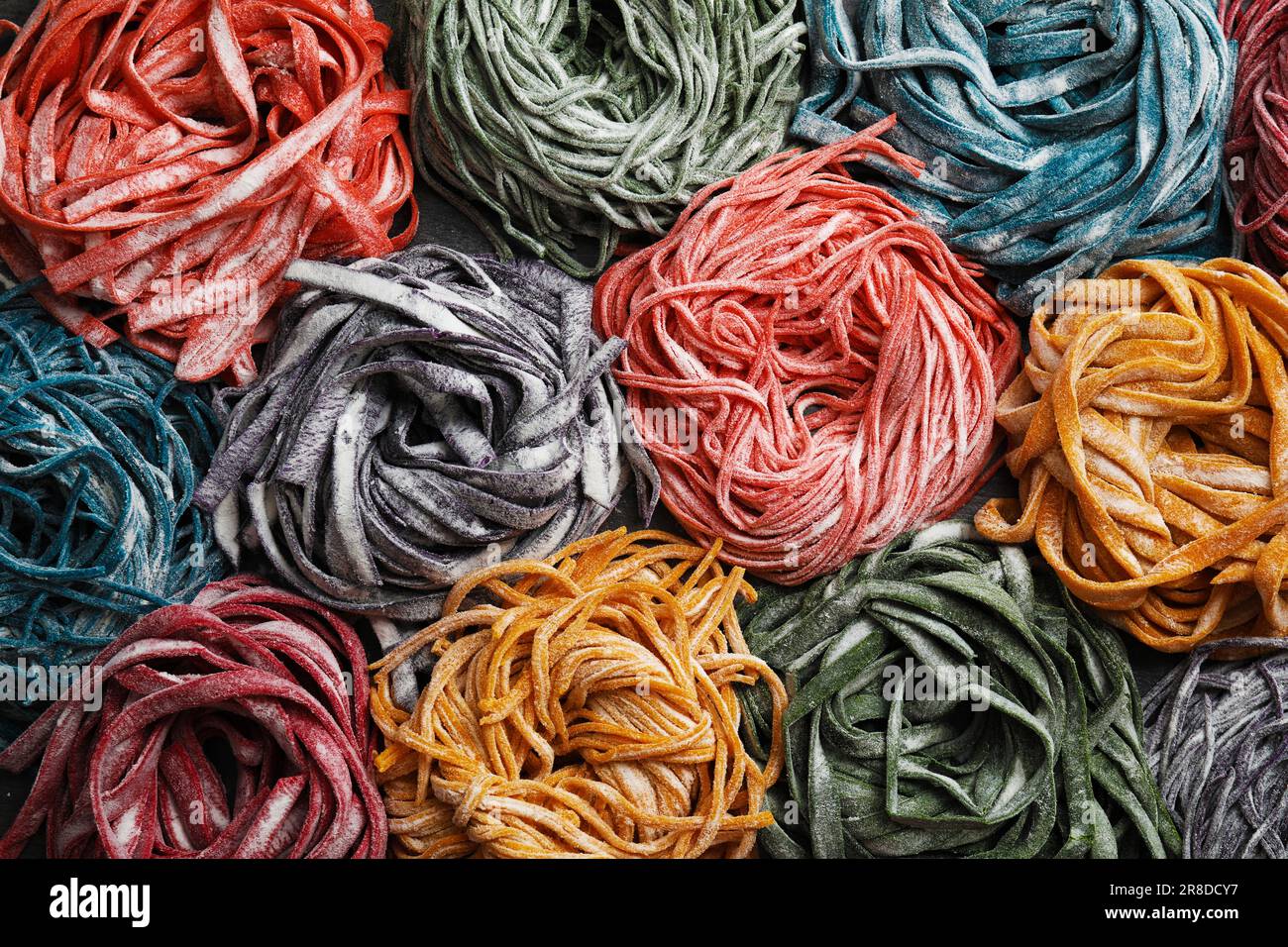 Rolled pasta painted with food colorings as background, top view Stock ...