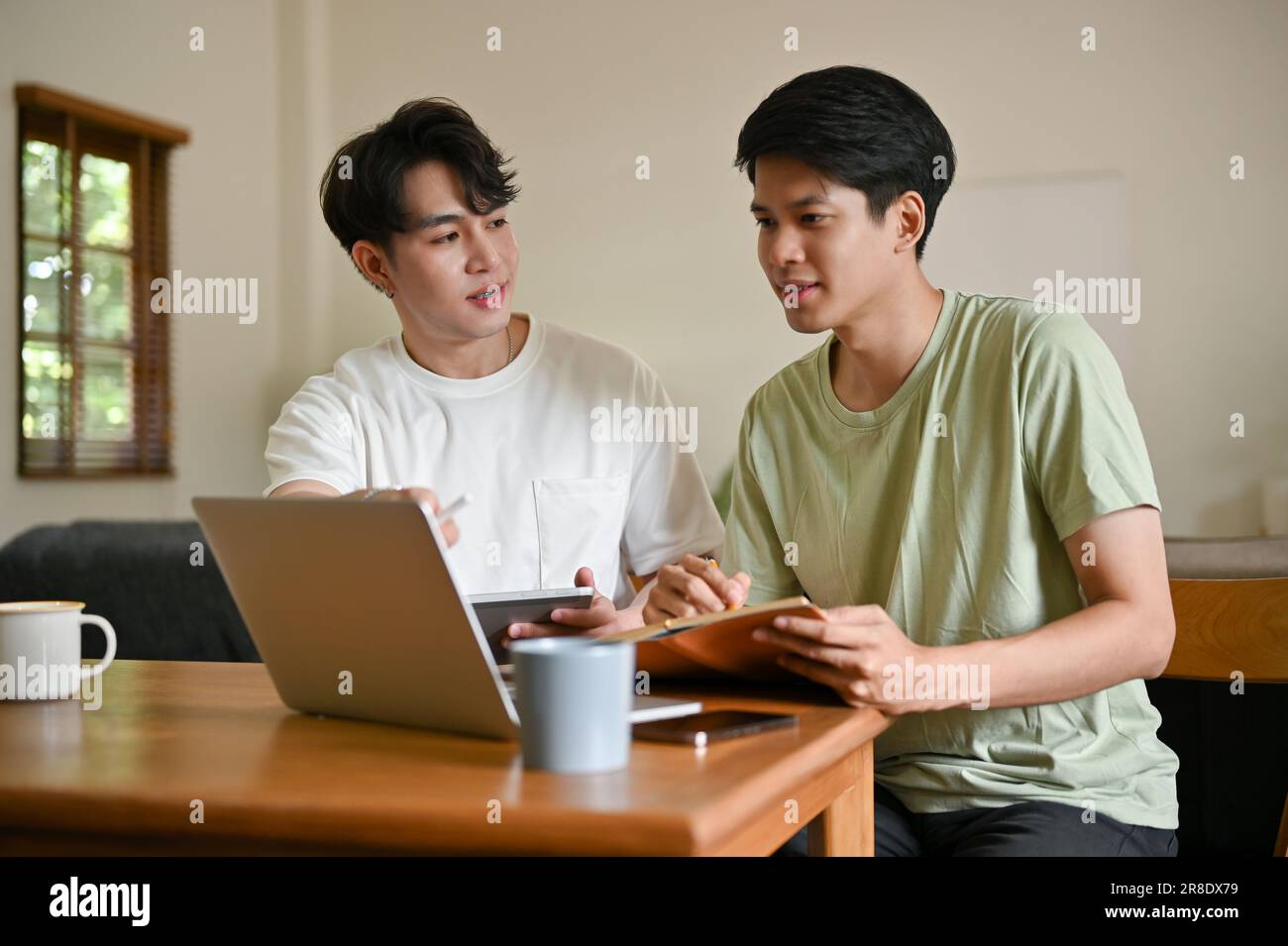 A smart young Asian male college student is explaining, tutoring, and ...
