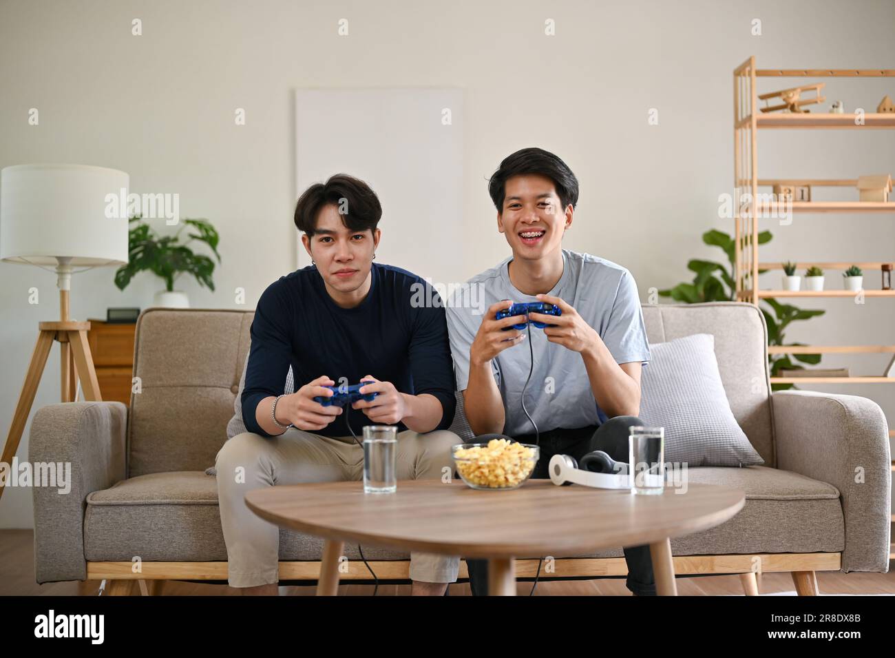 Two overjoyed and happy young Asian male friends are playing video ...