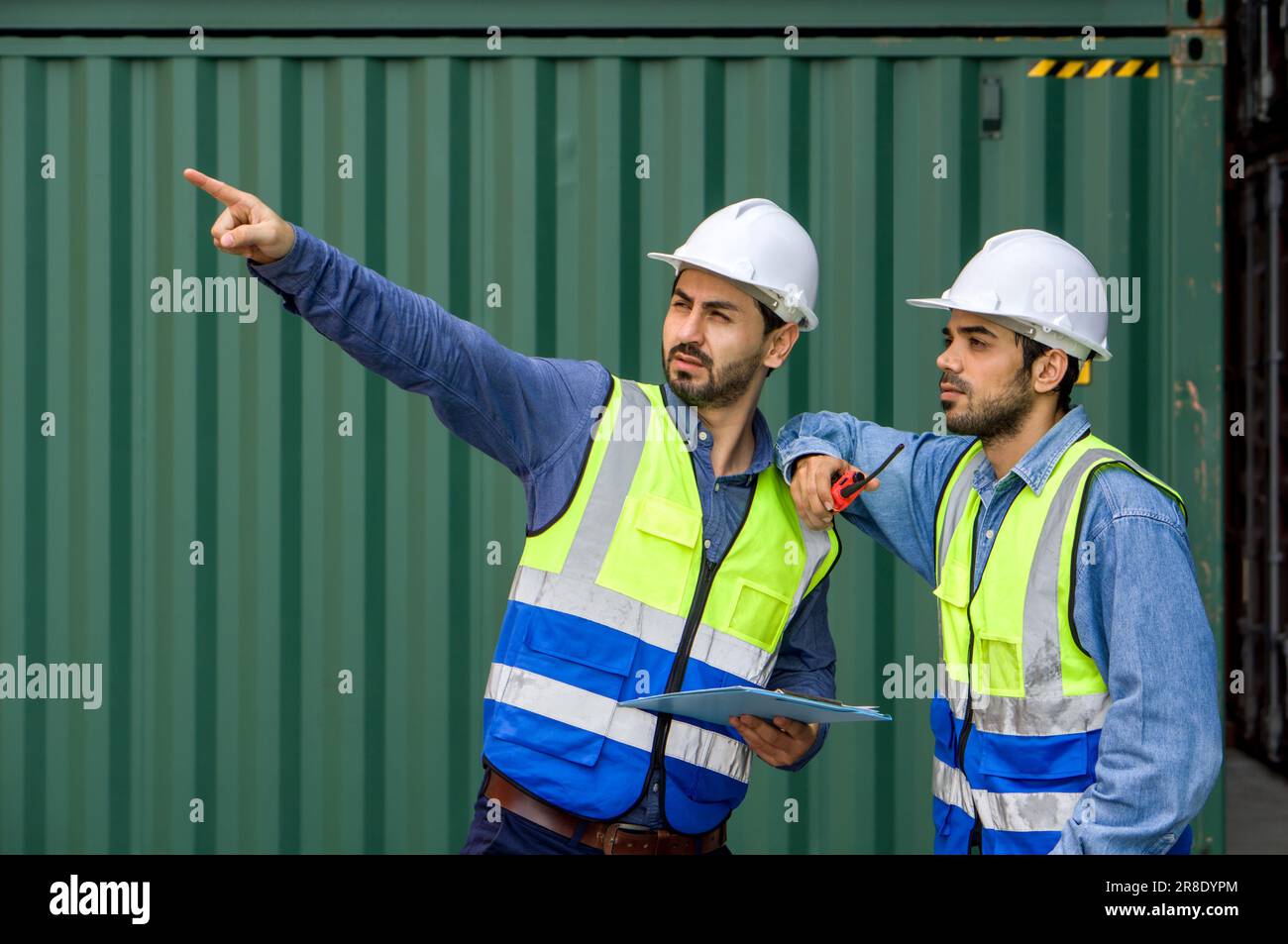 Young shipment worker pointing at container storage location while ...