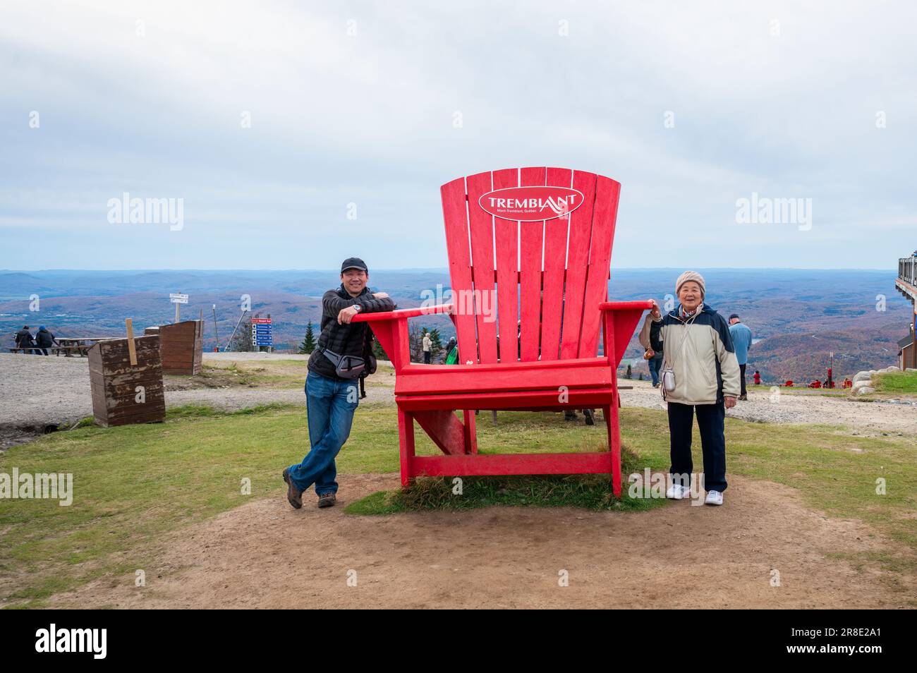 Senior Chinese woman and son posing for photos by giant red chair at ...