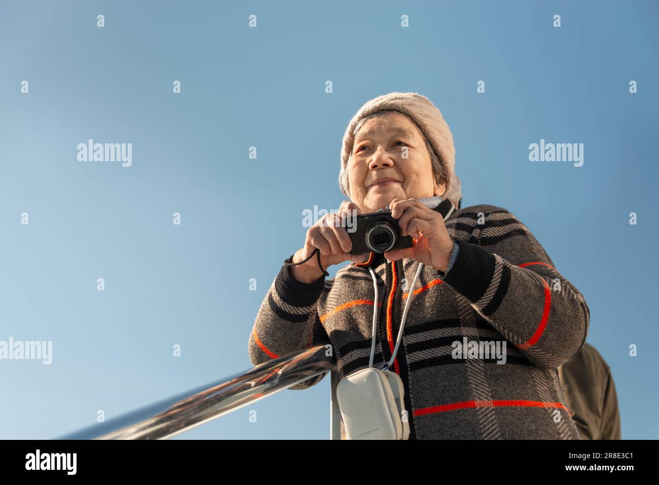 Senior Chinese tourist holding a camera in hand on cruise ship on Saint ...
