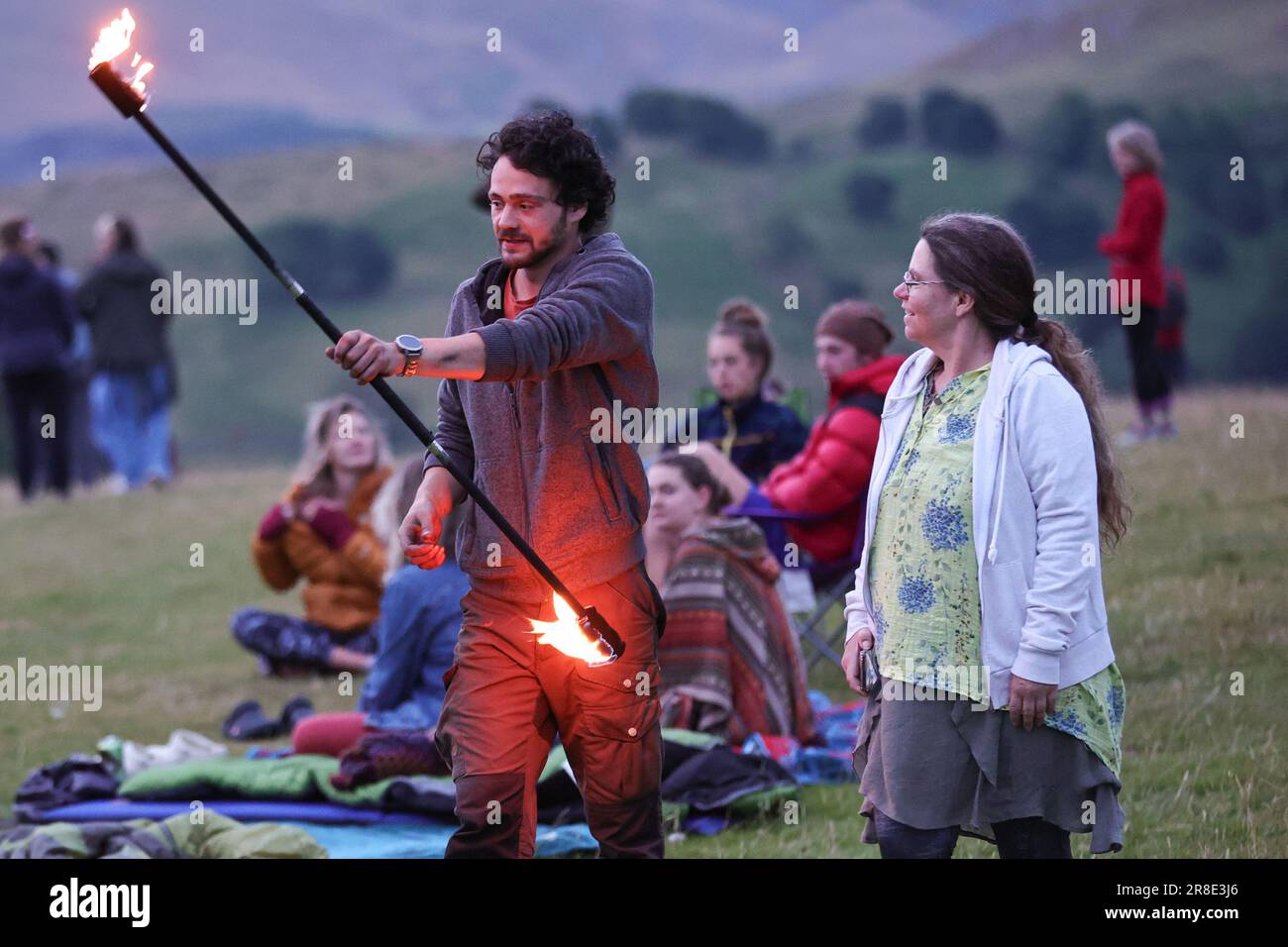 An attendee swirls a fire-stick around as they entertain onlookers ...