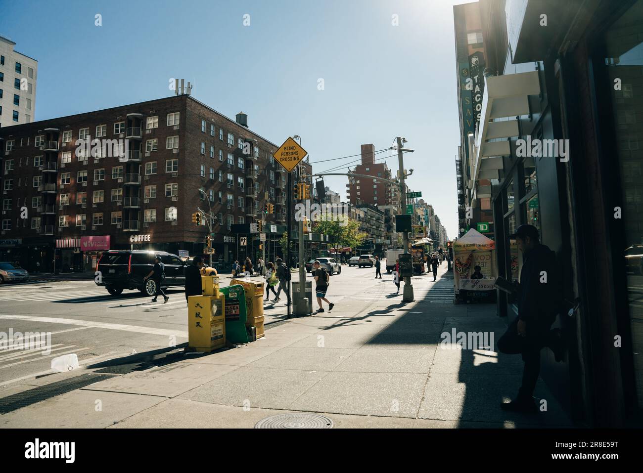 Busy street scene in New York City with groups of people walking across ...