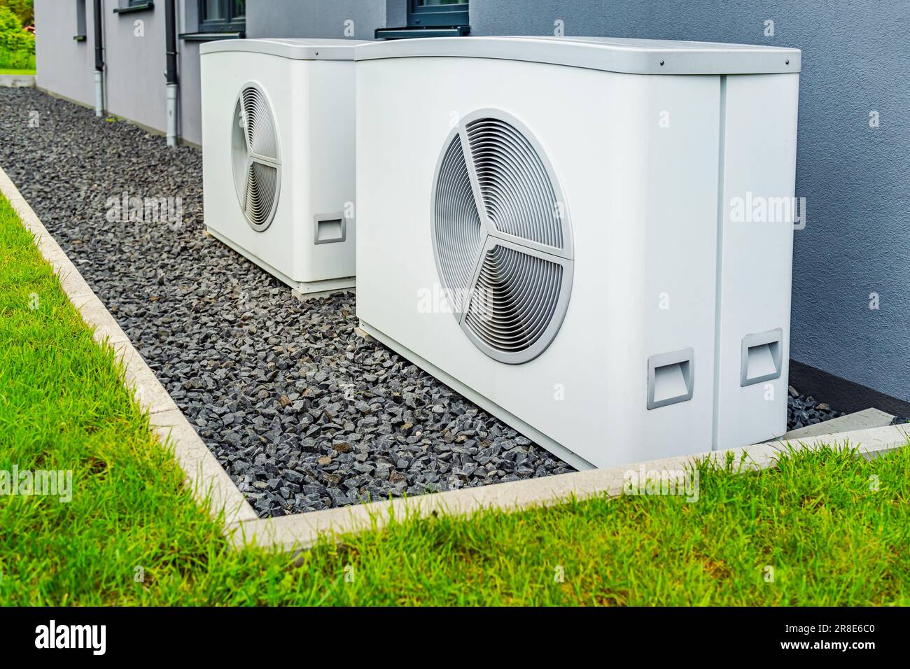 Two air source heat pumps installed outside of new and modern city house, green renewable energy ...