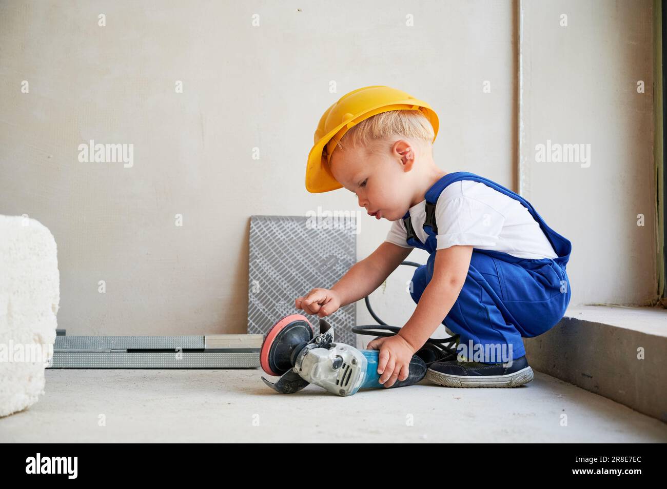Side view of adorable little boy construction worker holding electric ...