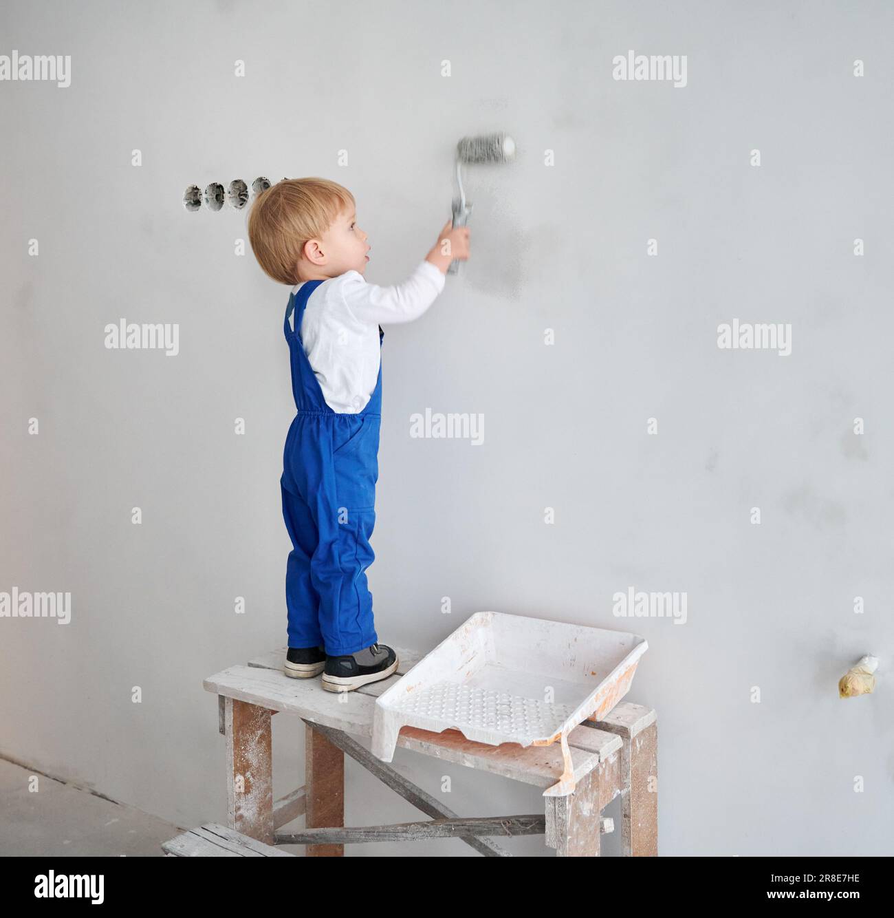 Little boy construction worker painting wall in apartment under ...