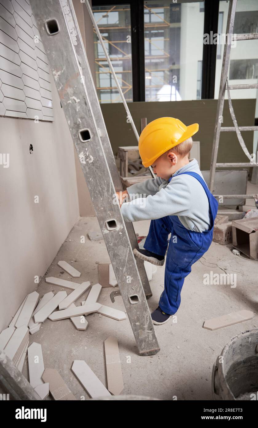 Child construction worker climbing ladder while working on home ...