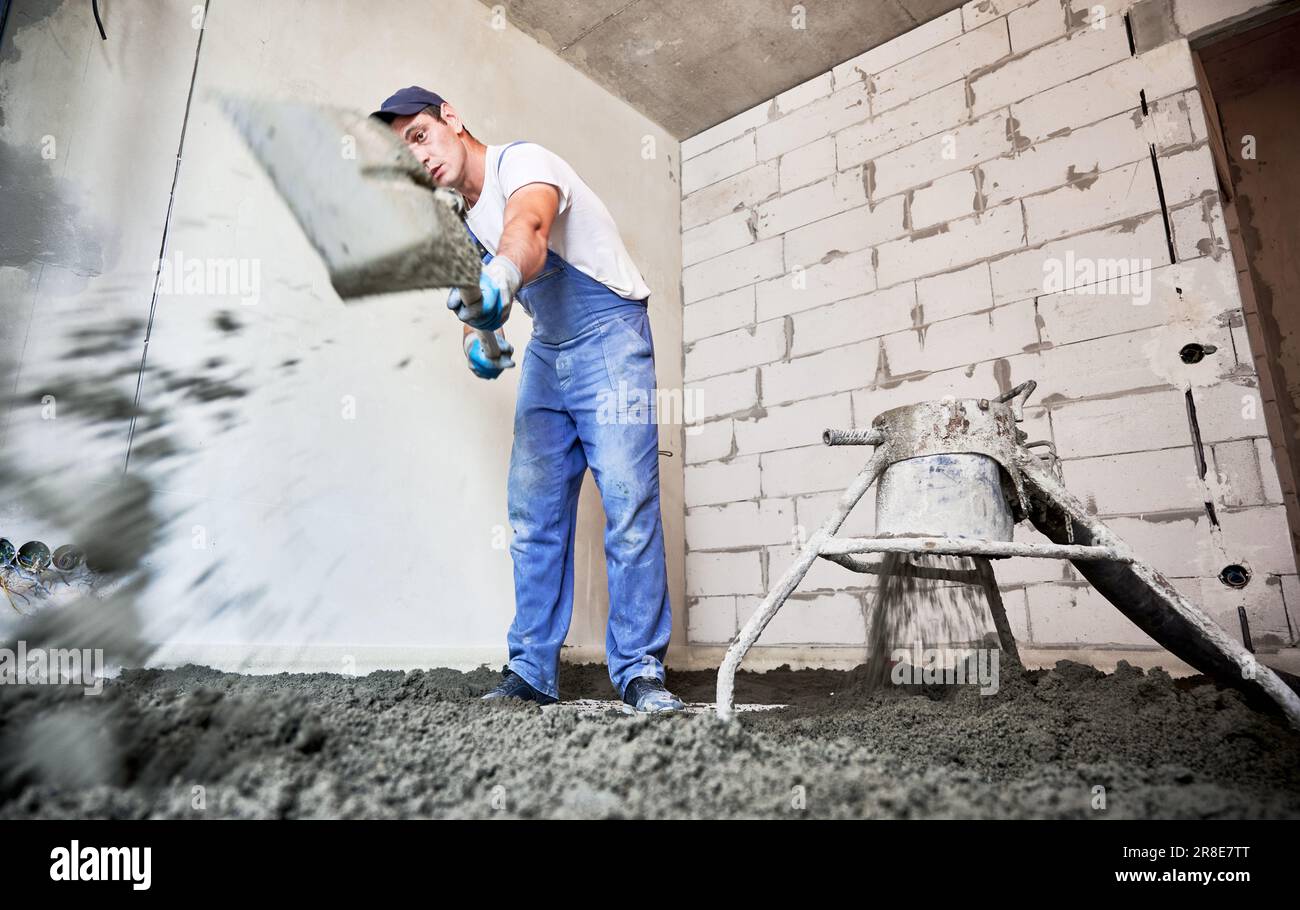 Full length of male worker using shovel while shoveling sand-cement mix ...