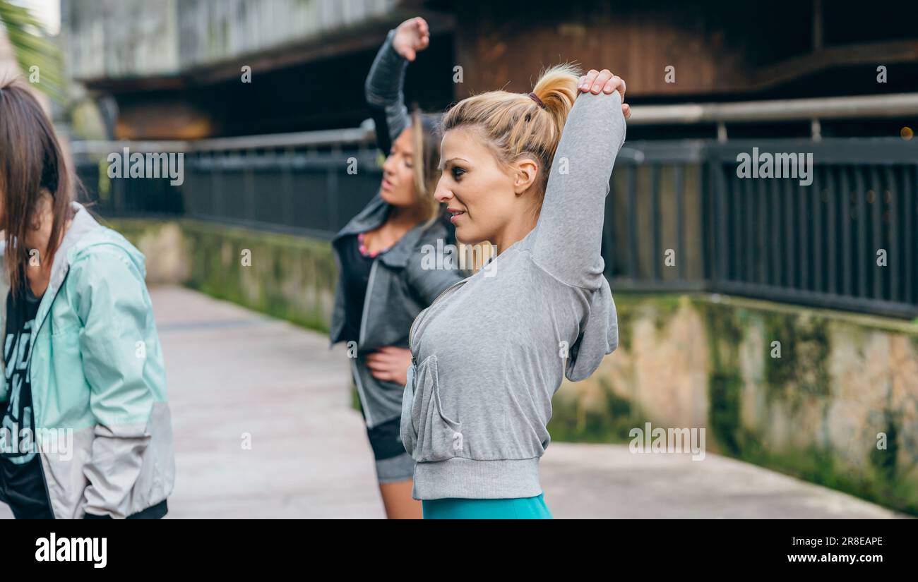 Woman runner stretching arms next to her female friends before training ...