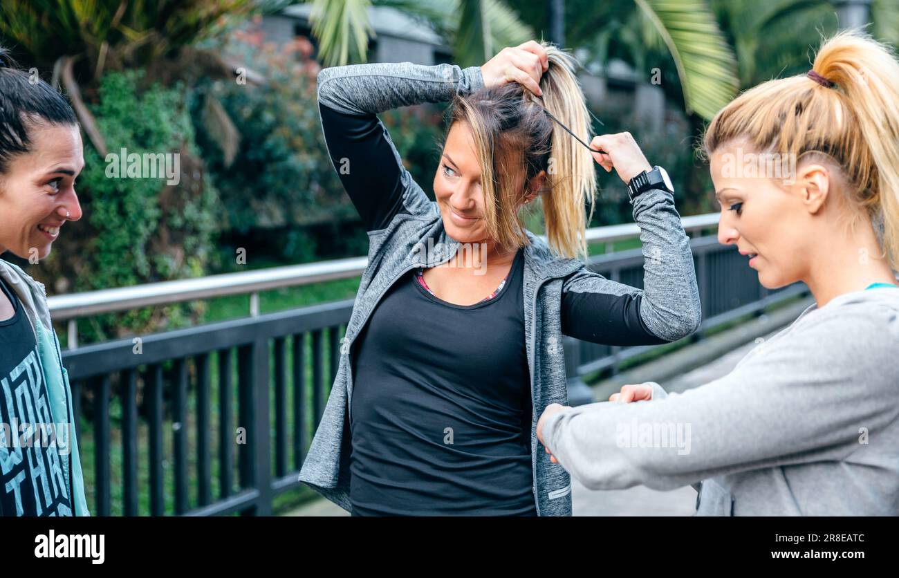 Blonde woman runner tying her hair in a ponytail before training Stock ...