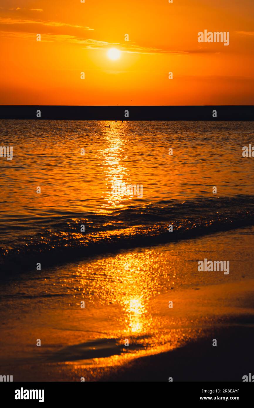 Reflection of sunlight over sea surface at sunset. Orange and gold blue ...