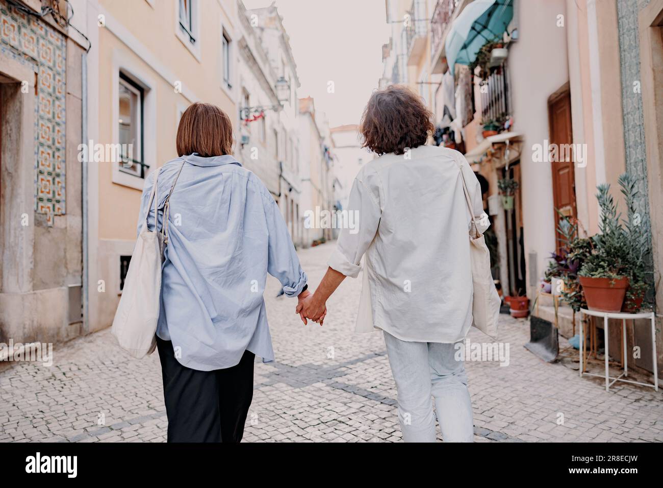 Back view of couple hugging and walking on Lisbon street, enjoying ...