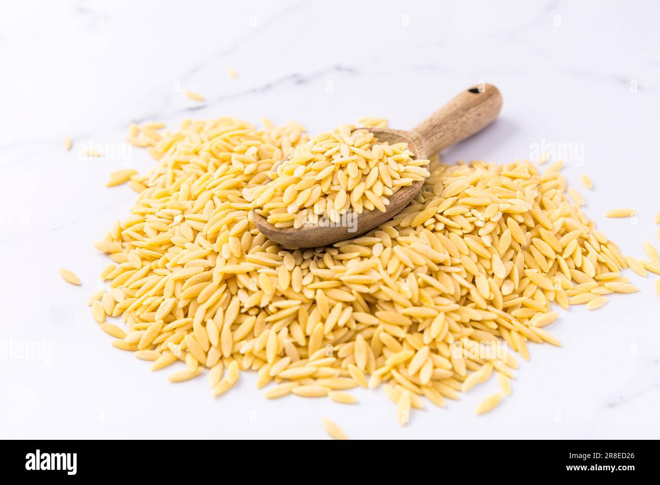 Raw orzo pasta (risoni) with wooden spoon Stock Photo - Alamy
