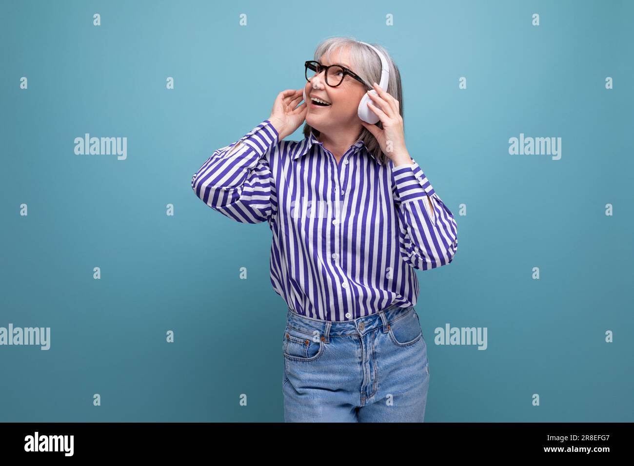 smiling old generation woman with gray hair listening to music with ...