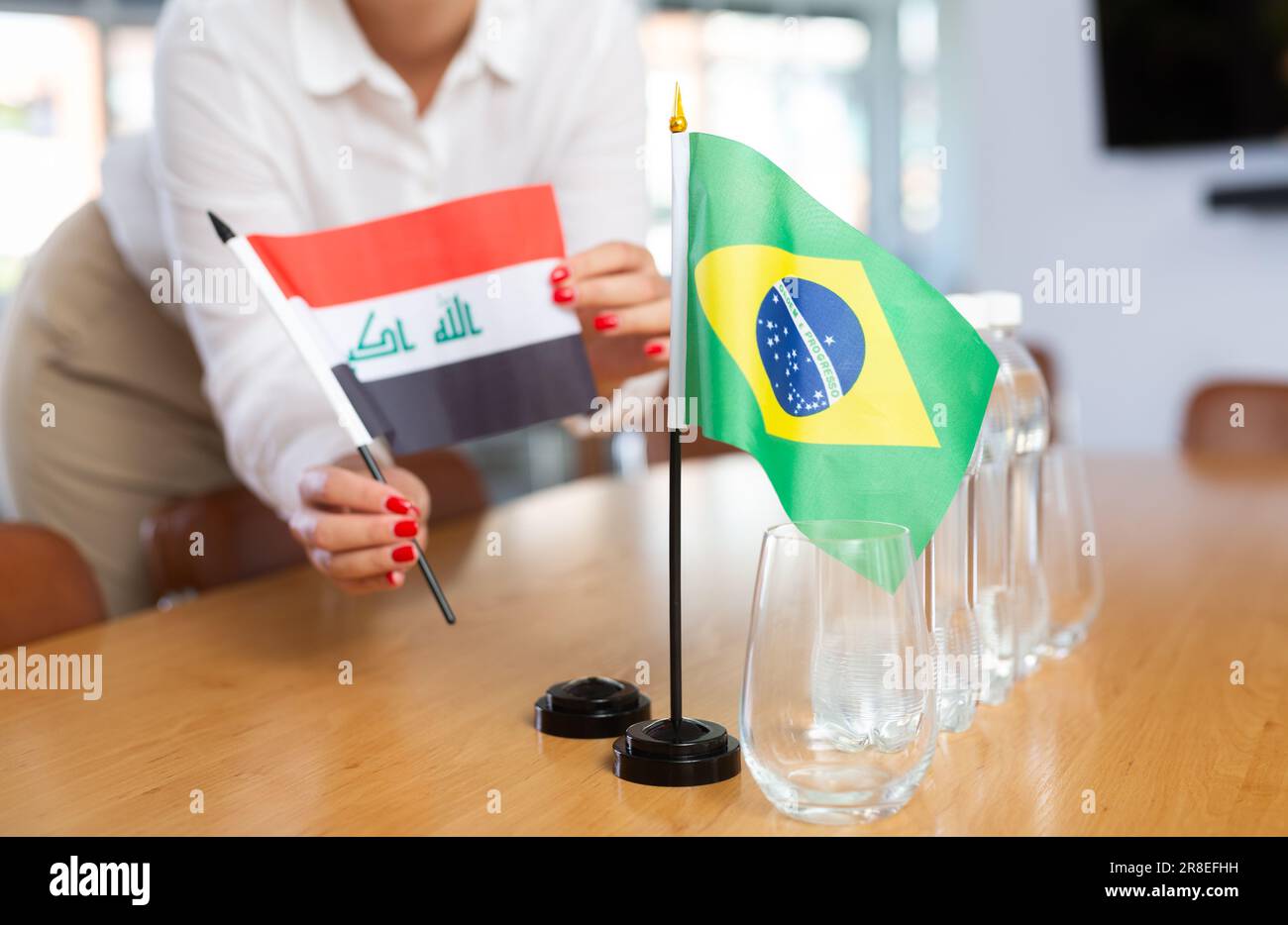 Female secretary places flags of the Iraq and Brazil flag on table ...