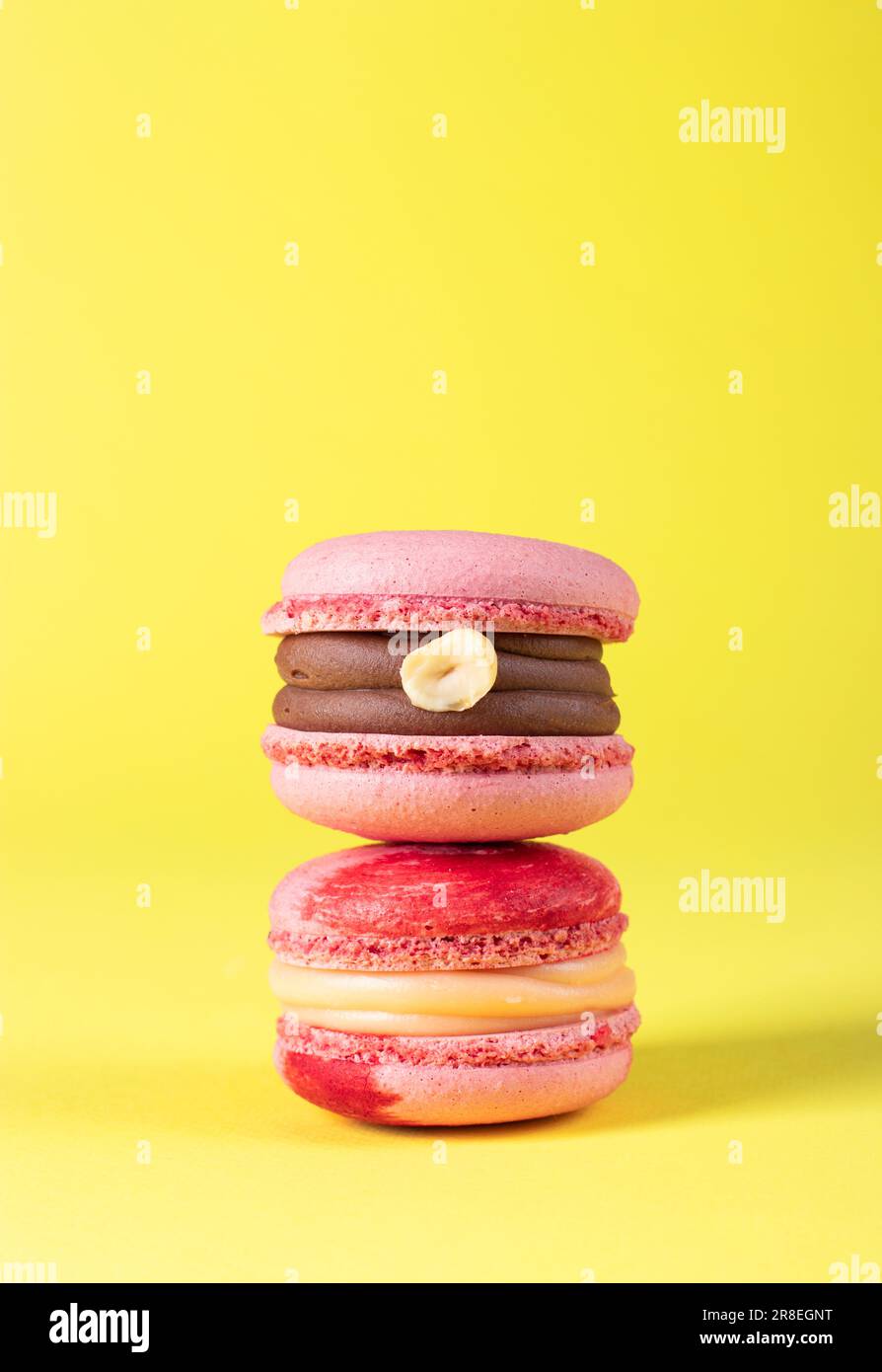 Two pink macarons with hazelnuts and caramel on yellow background ...