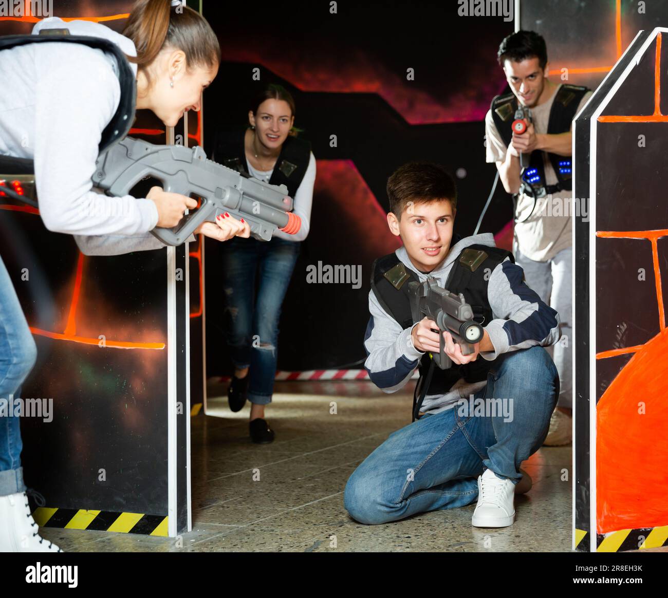 Excited young people playing enthusiastically laser tag game two teams ...