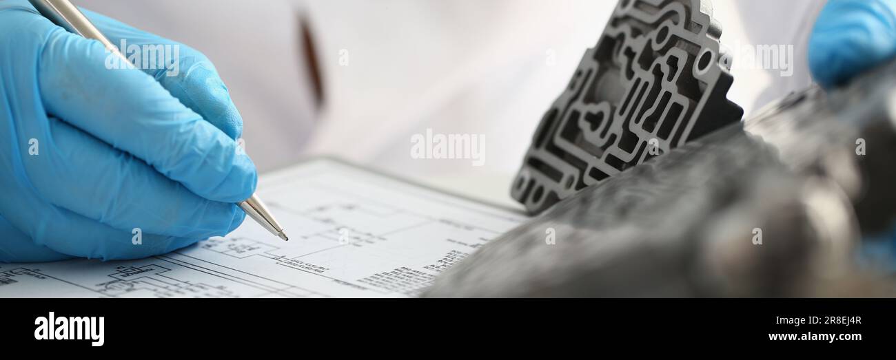 Scientist mechanic in gloves conducts technical research of car gearbox ...
