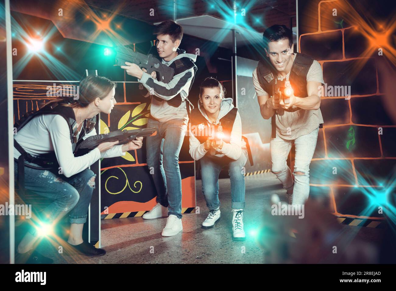 Modern young people with laser pistols playing laser tag on dark Stock ...