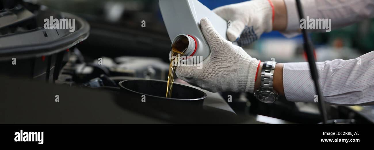 Closeup of experienced mechanic checking and pouring oil into special ...