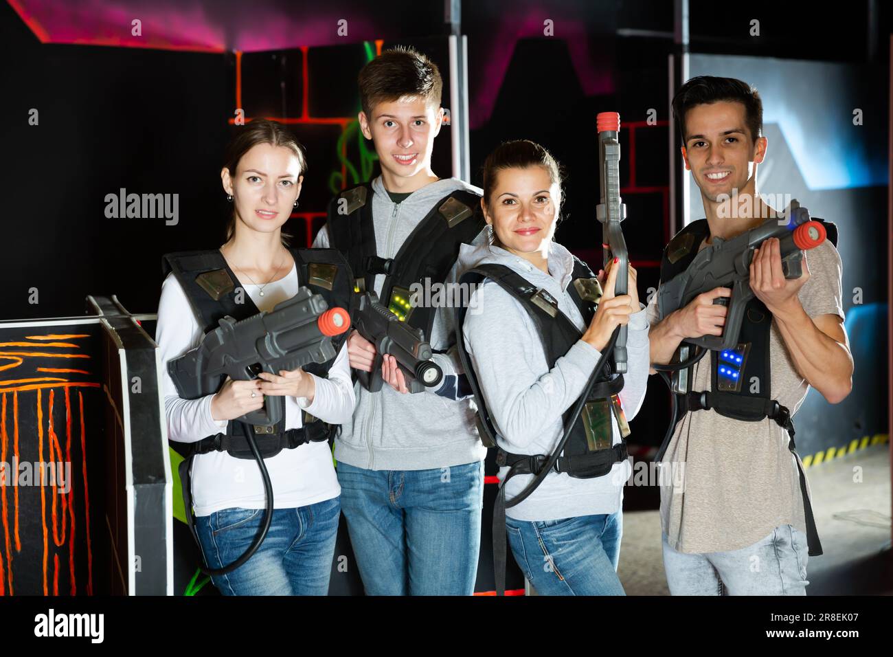 Four happy young men an women posing with laser pistols in their hands ...