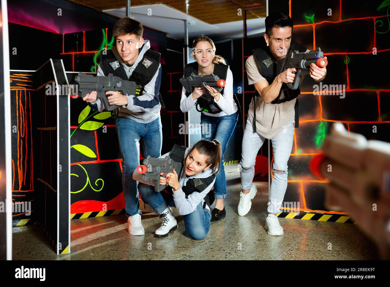 Group of young people playing laser tag game with laser guns Stock ...