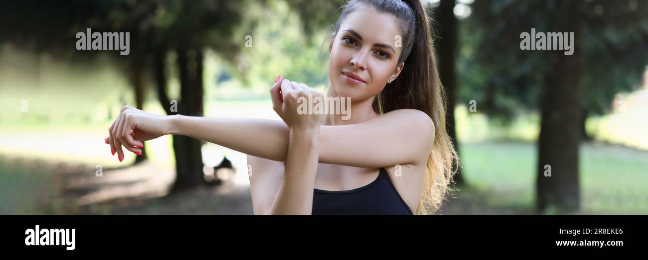 Portrait of beautiful sports woman stretches arms in park Stock Photo ...