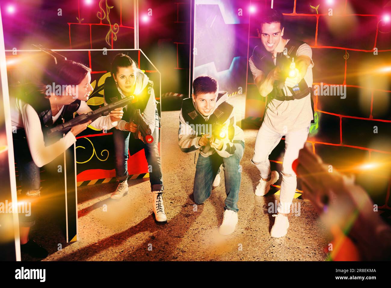 Group of young people playing laser tag game with laser guns Stock ...