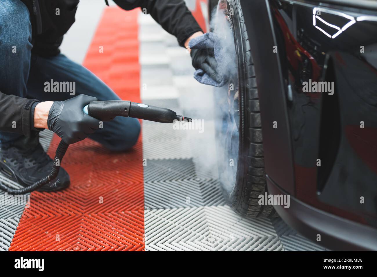 Low angle view of a hot steam machine used for deep cleaning of wheels ...