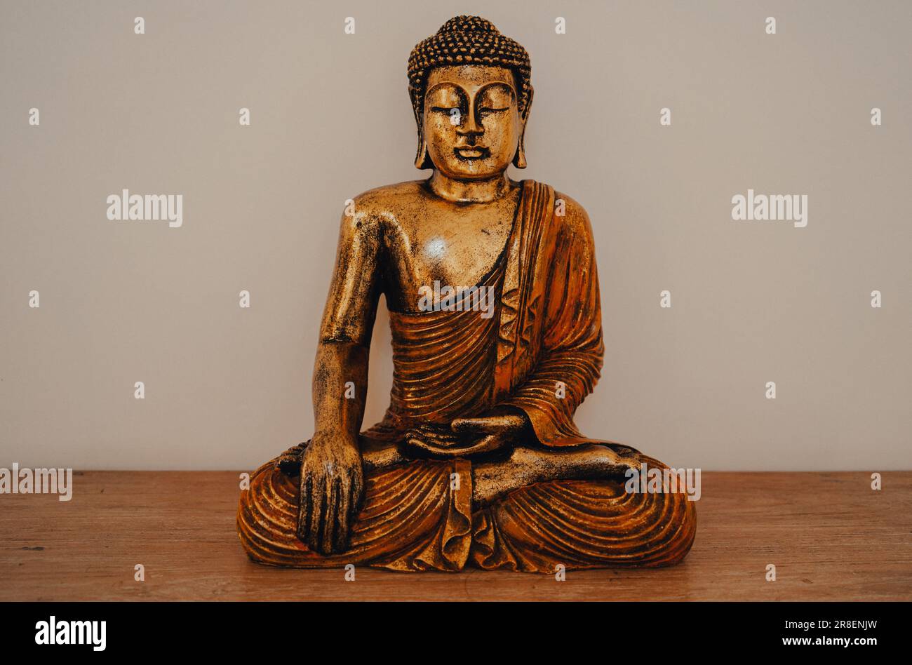 Golden buddha statue in sitting meditation pose on white wall ...