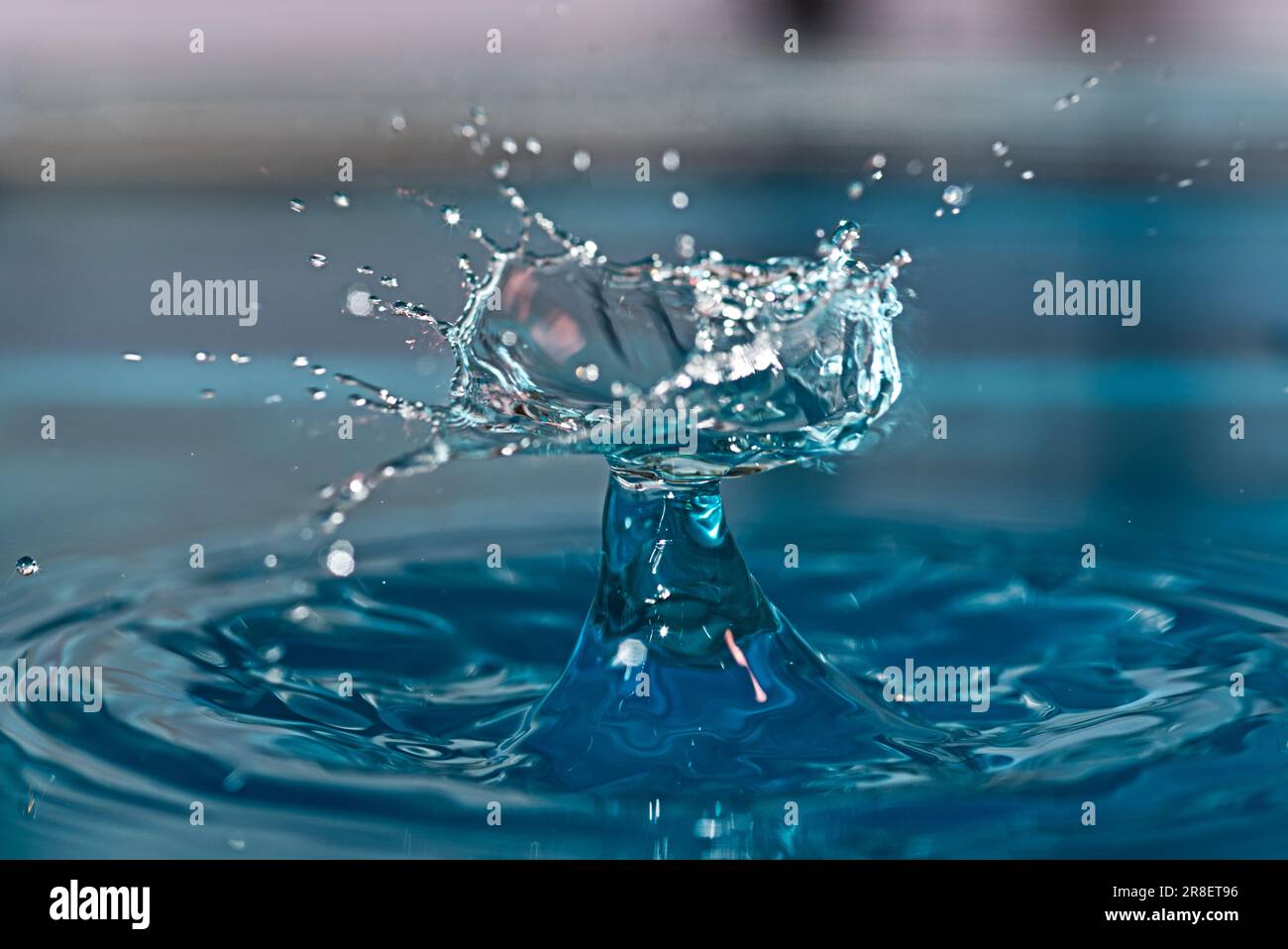 A vibrant blue liquid is being poured into a pool of water Stock Photo ...