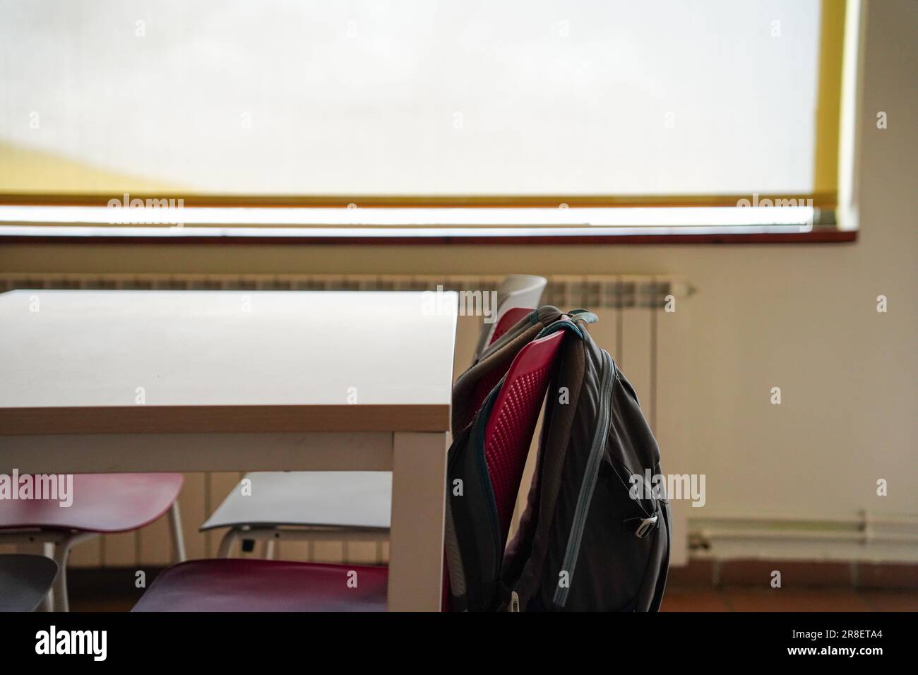 a backpack hanging on a chair in a school classroom. Back to school ...