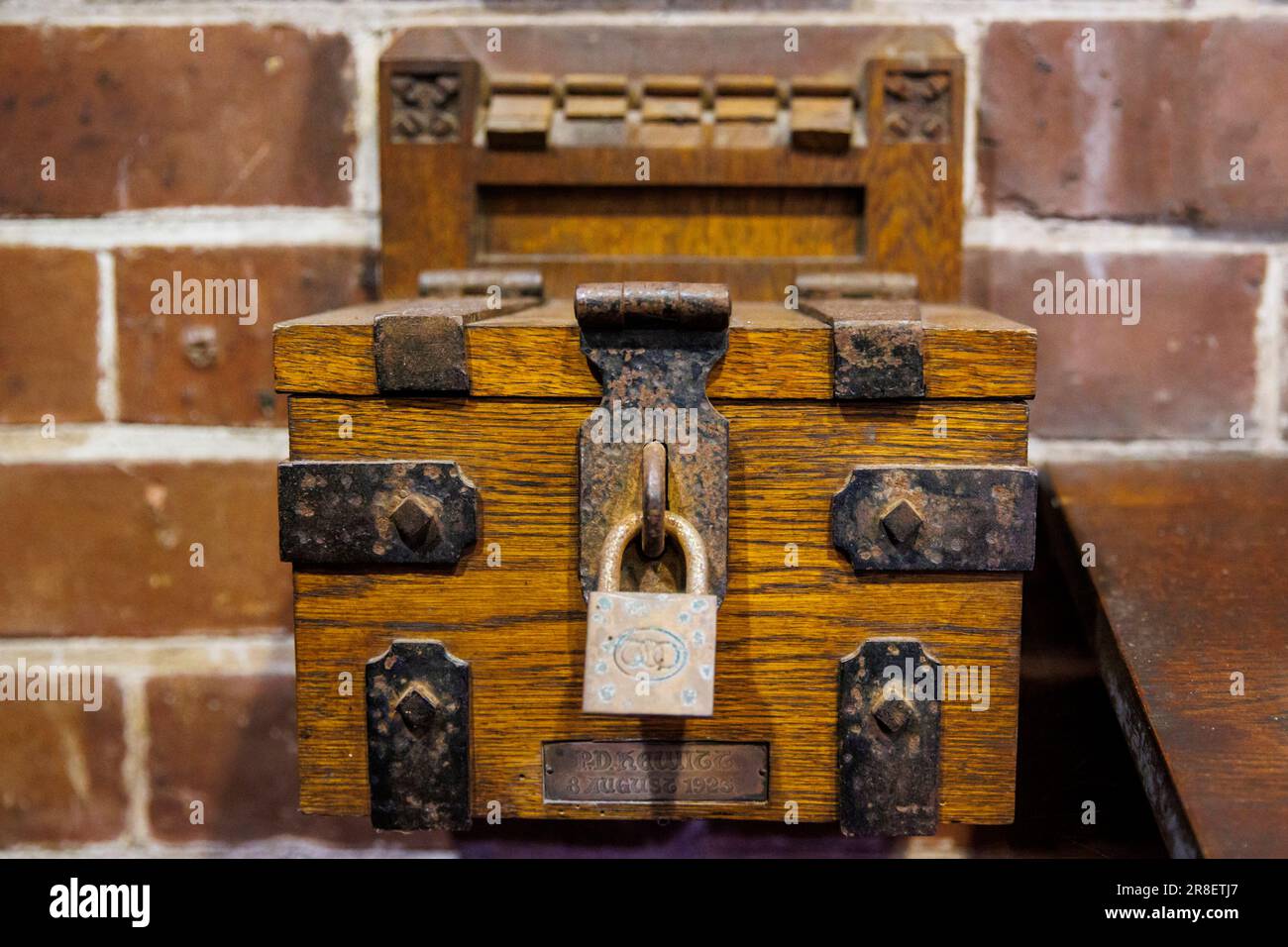 Wooden collection box padlocked attached to brick wall in a church ...