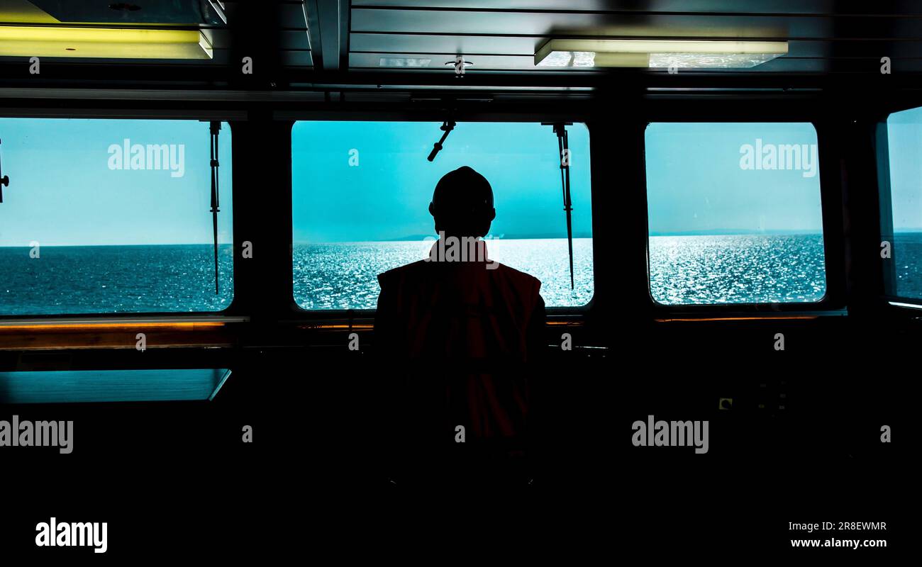 A silhouette of the captain standing near the window on a ship, taking ...
