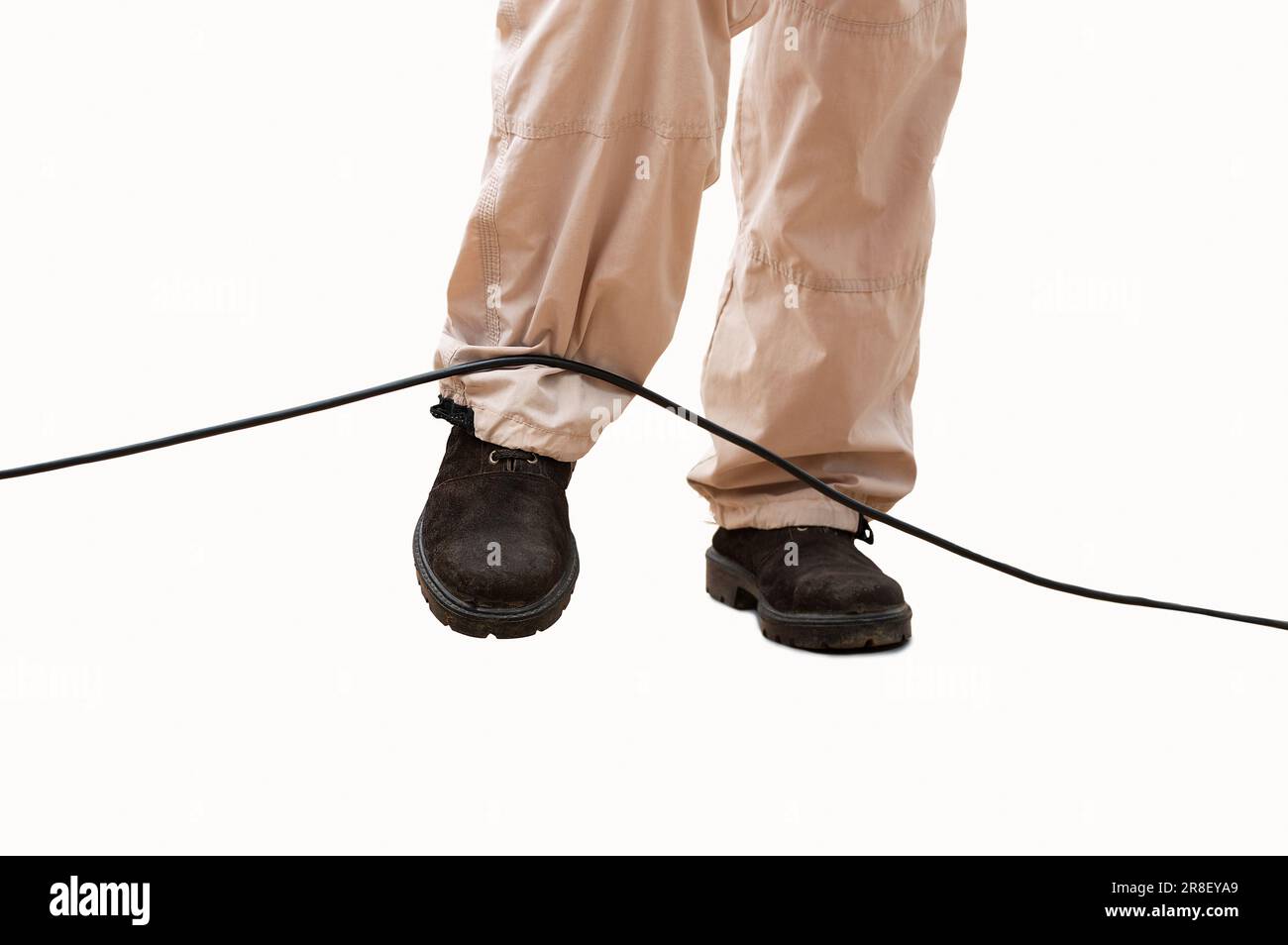 Close-up of a man's legs tripping over an electrical cord with white ...