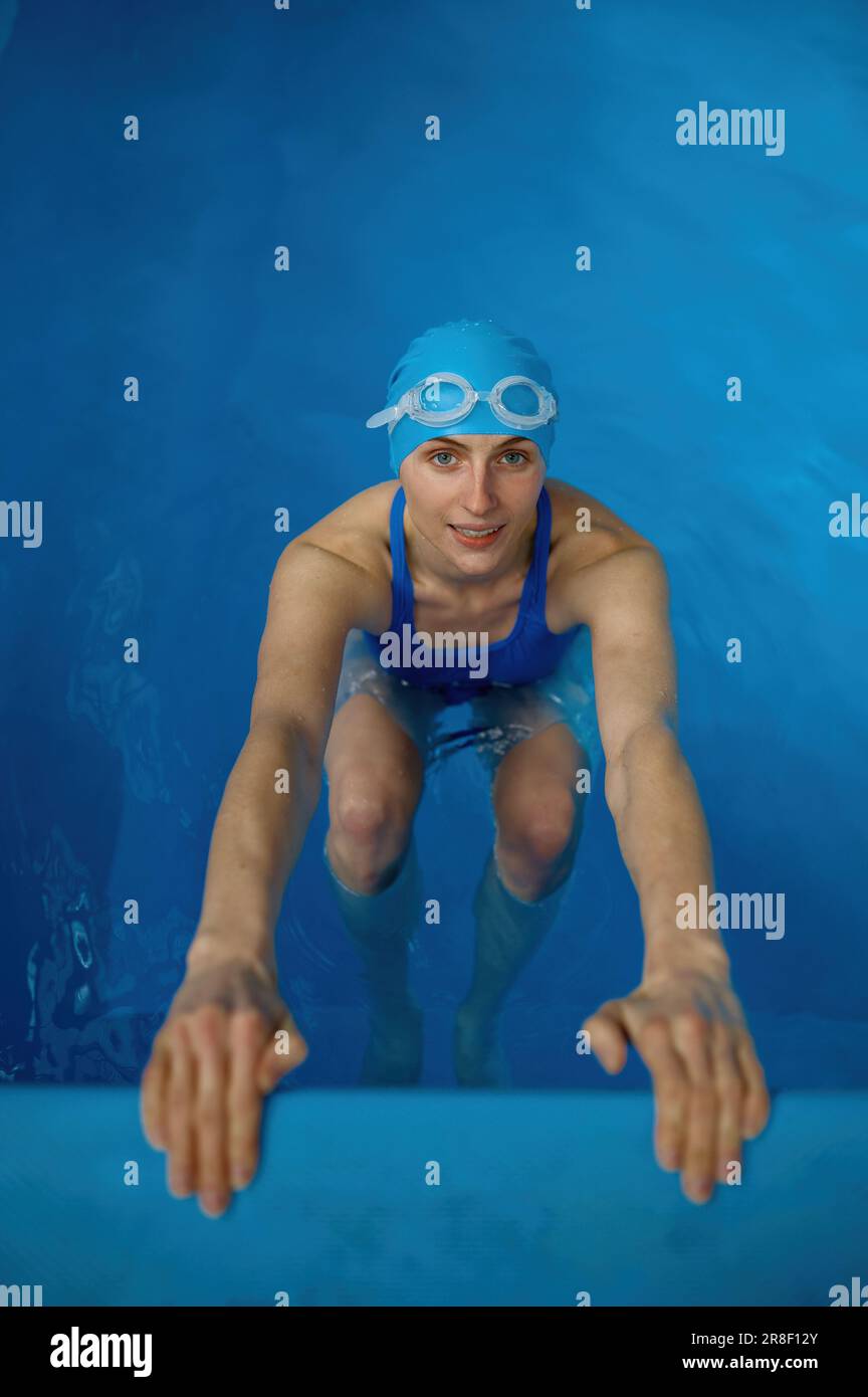 Top view on young sportswoman training backstroke in indoor swimming ...