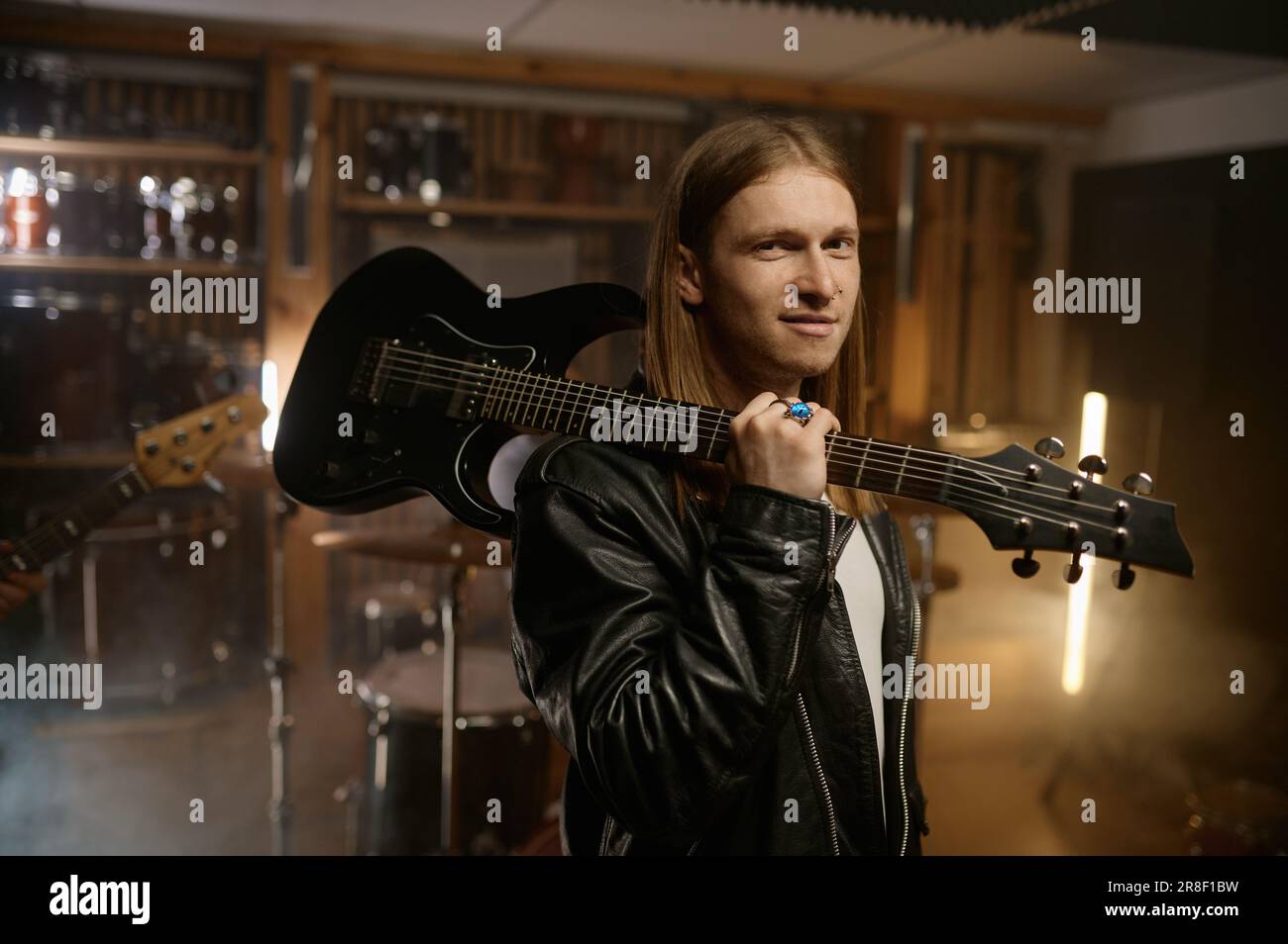 Portrait of smiling rock guitarist carrying music instrument on ...