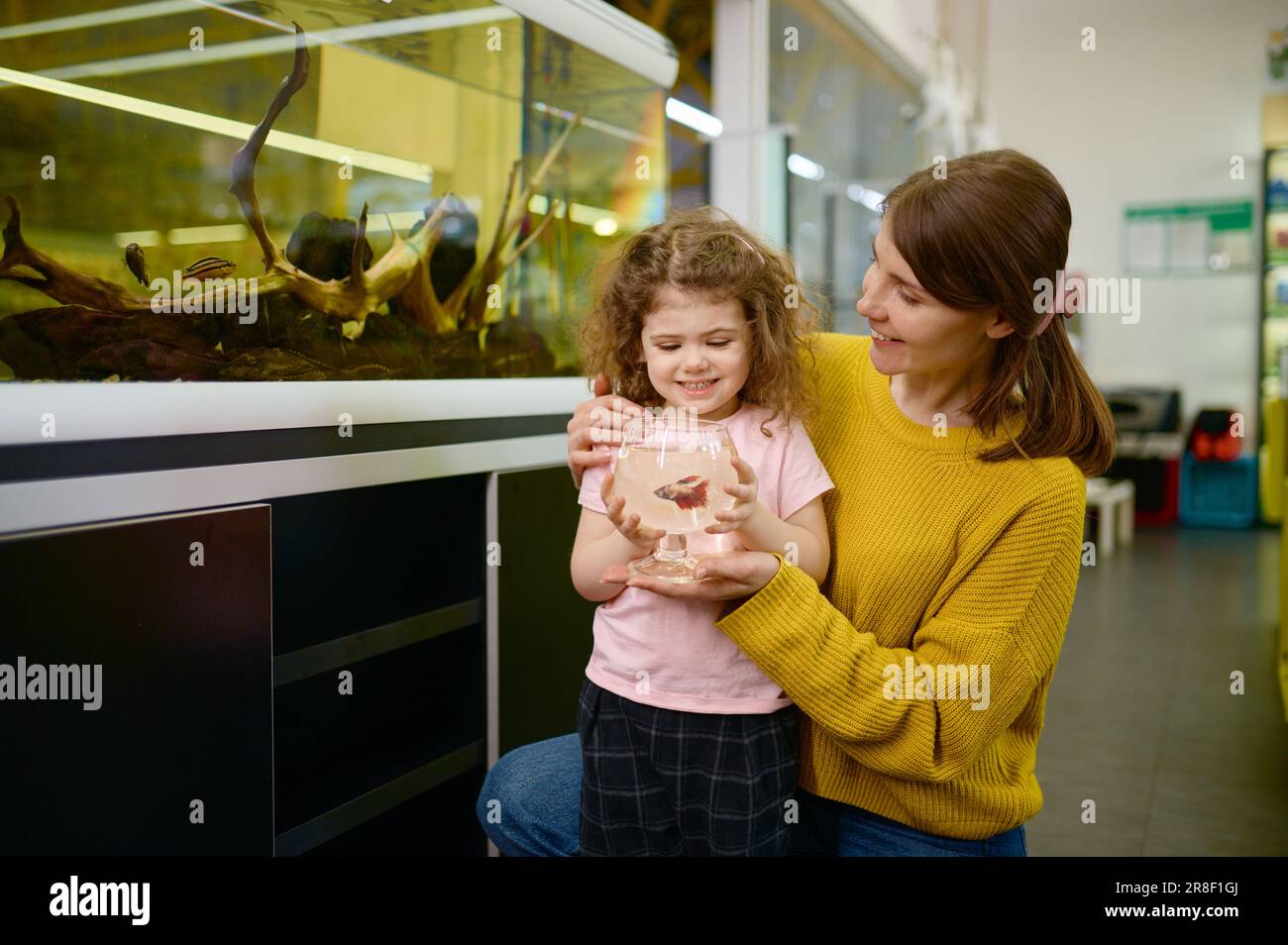 Happy mother and little daughter bought fish at pet shop Stock Photo ...