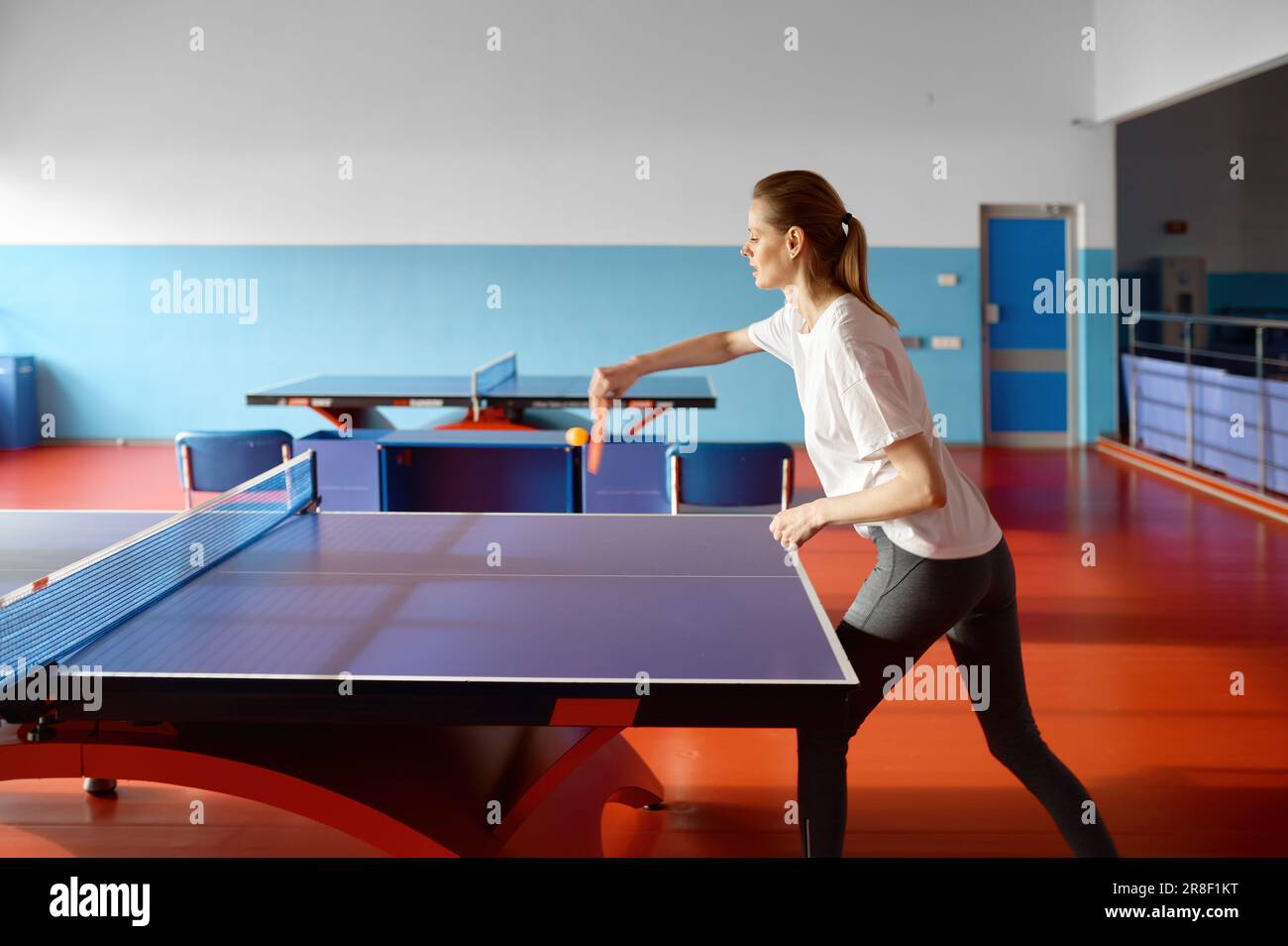 Young woman kicking ball playing table tennis at sport club Stock Photo ...