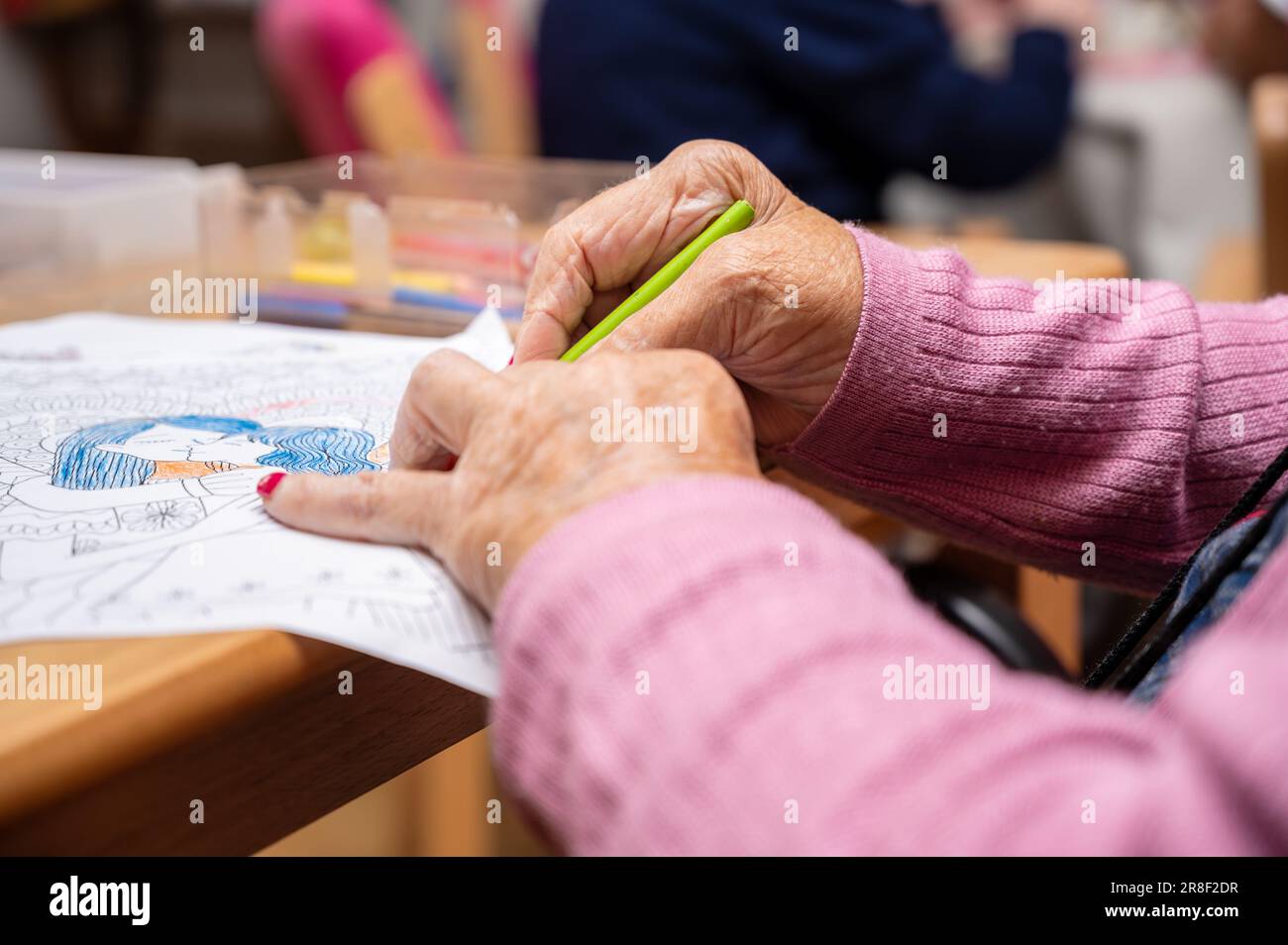 Elderly woman painting color on her drawing. Hobby at nursing home ...