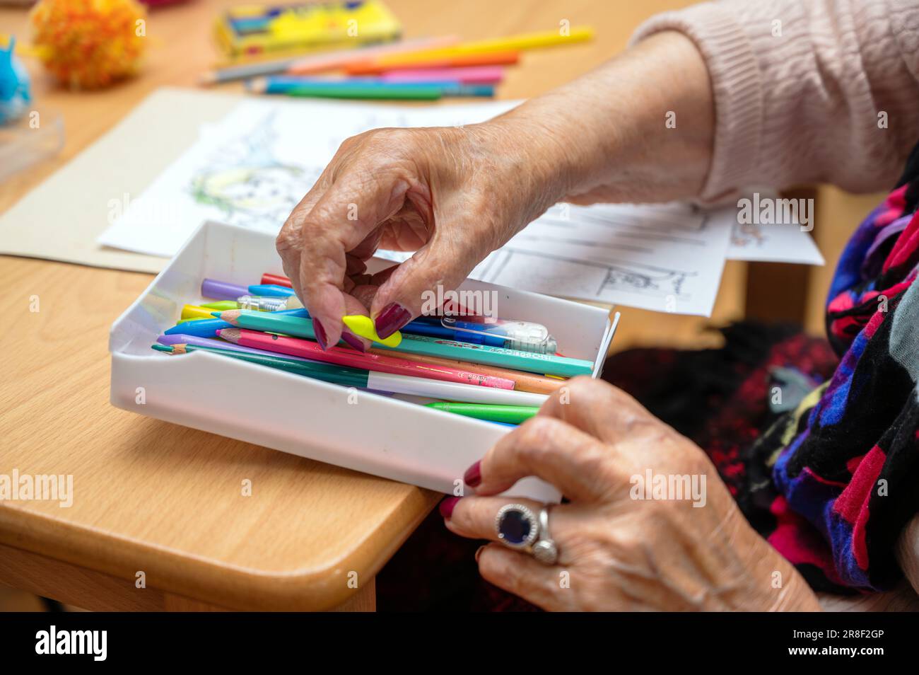 Elderly woman painting color on her drawing. Hobby at nursing home ...