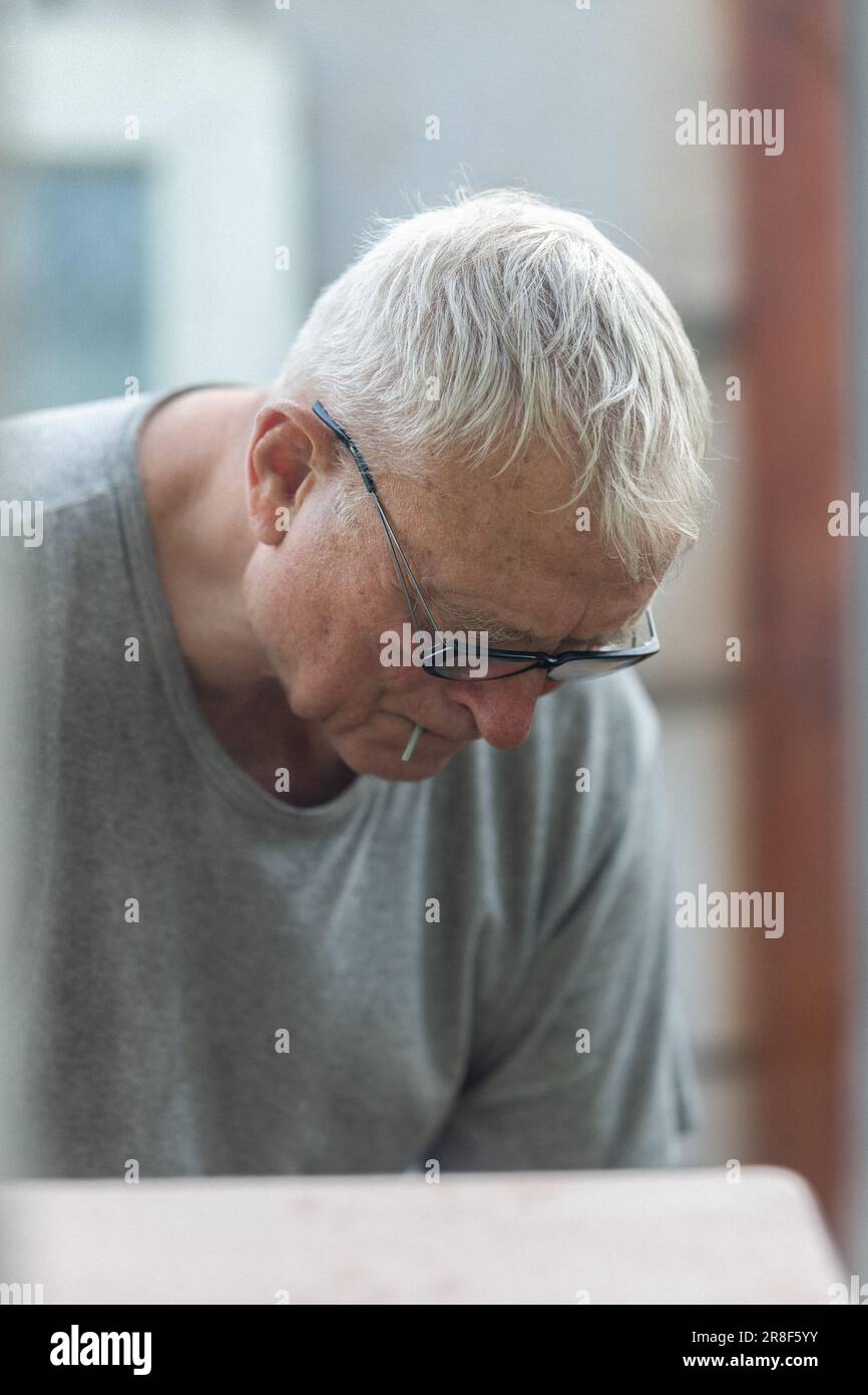 Caucasian pensioner with gray hair hammering at DIY home workshop ...